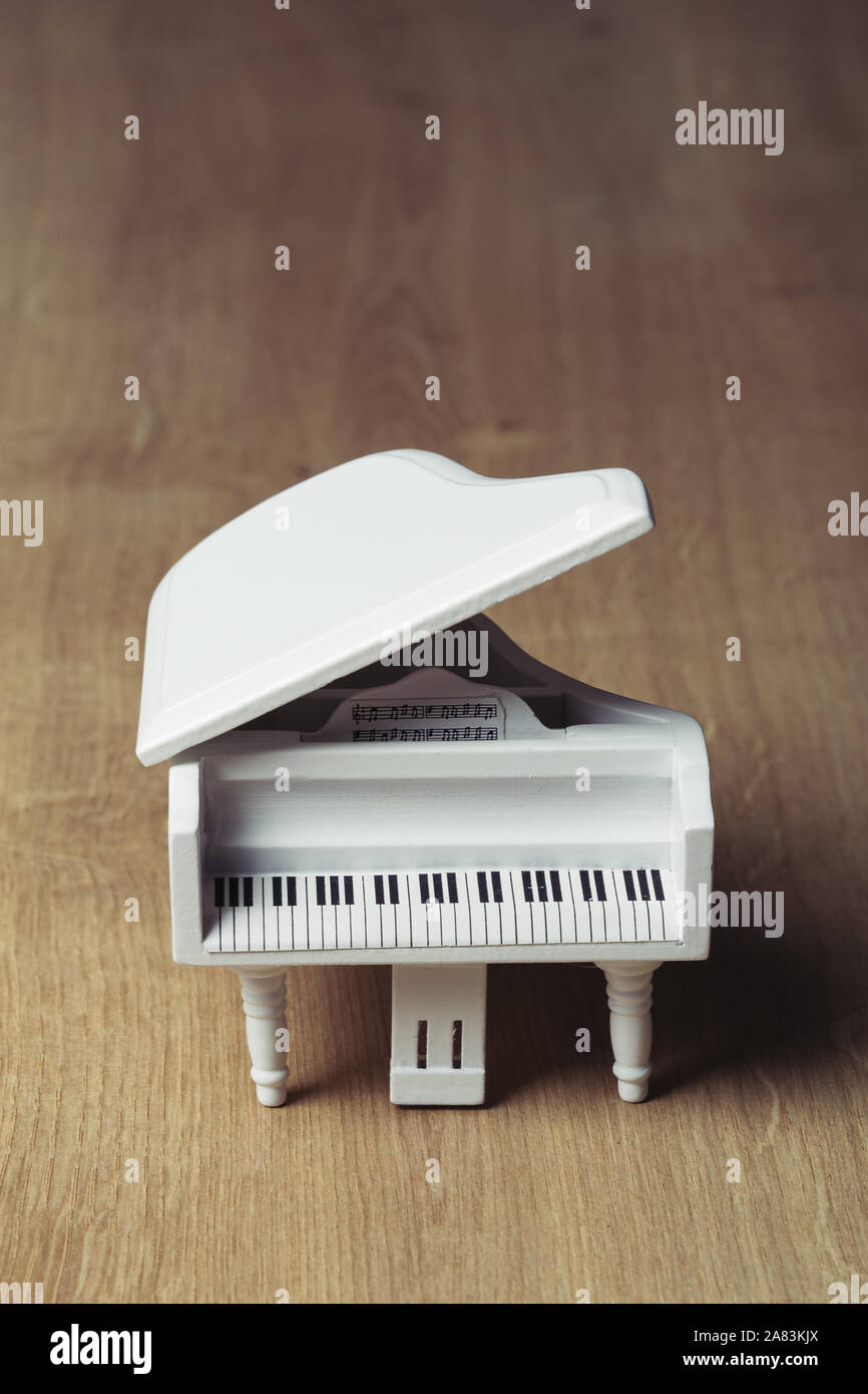 Tiny white wooden piano music close up still on a wooden background ...