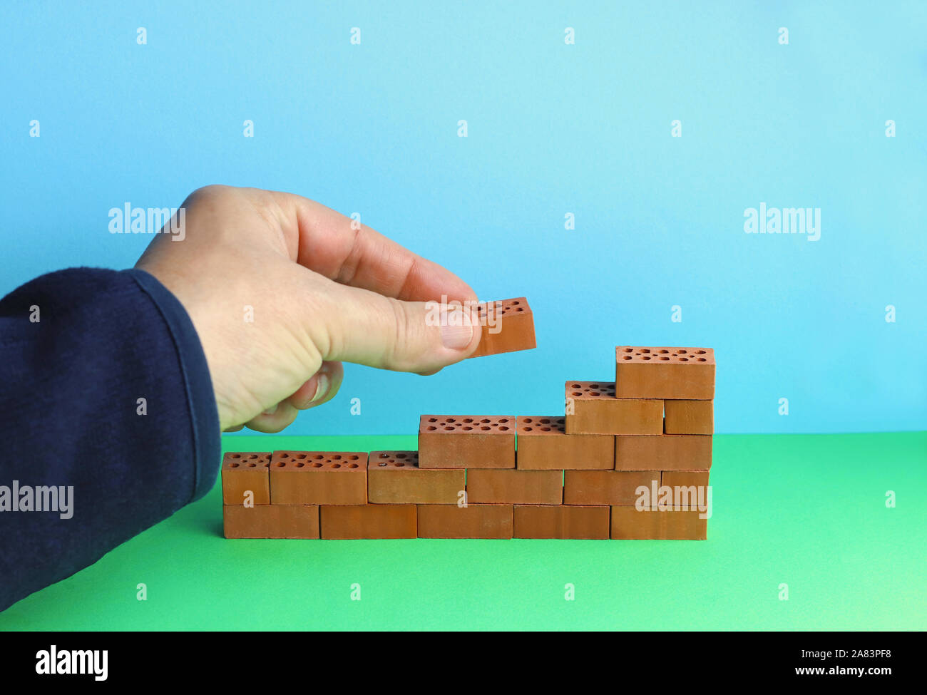 hand building a wall with small brick stones Stock Photo - Alamy