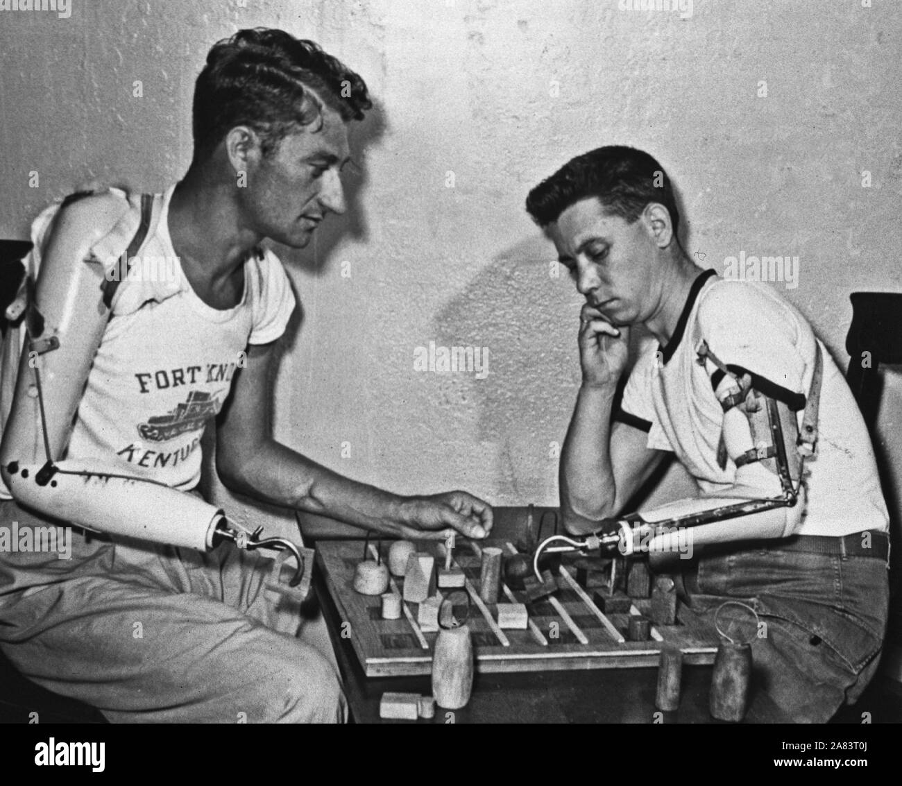 Two men with prosthetic arms playing a game of checkers as part of ...