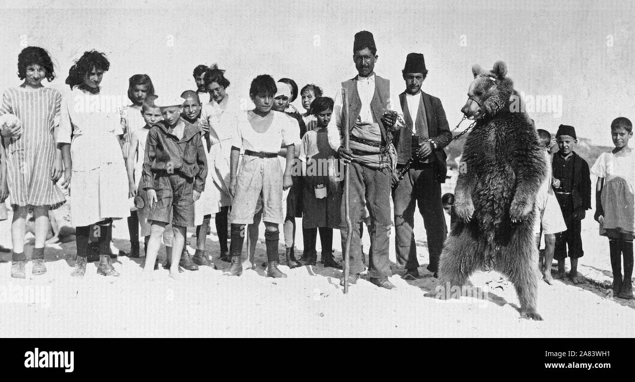 Group portrait of dancing bear, trainer, and children at Floria Beach ...