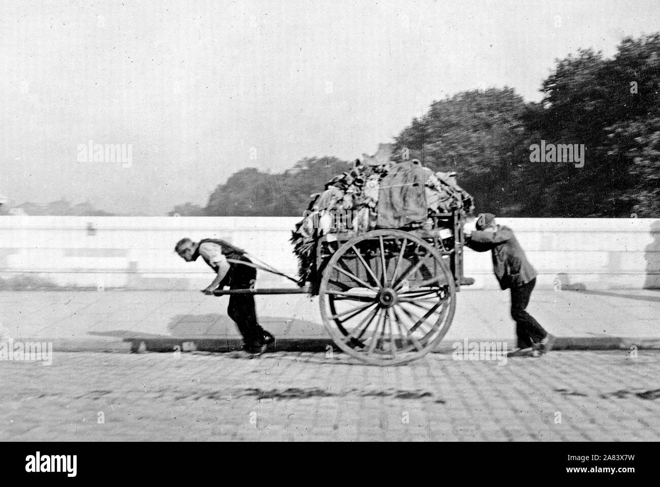 Photo shows an elderly man pulling and a young man pushing a large two ...