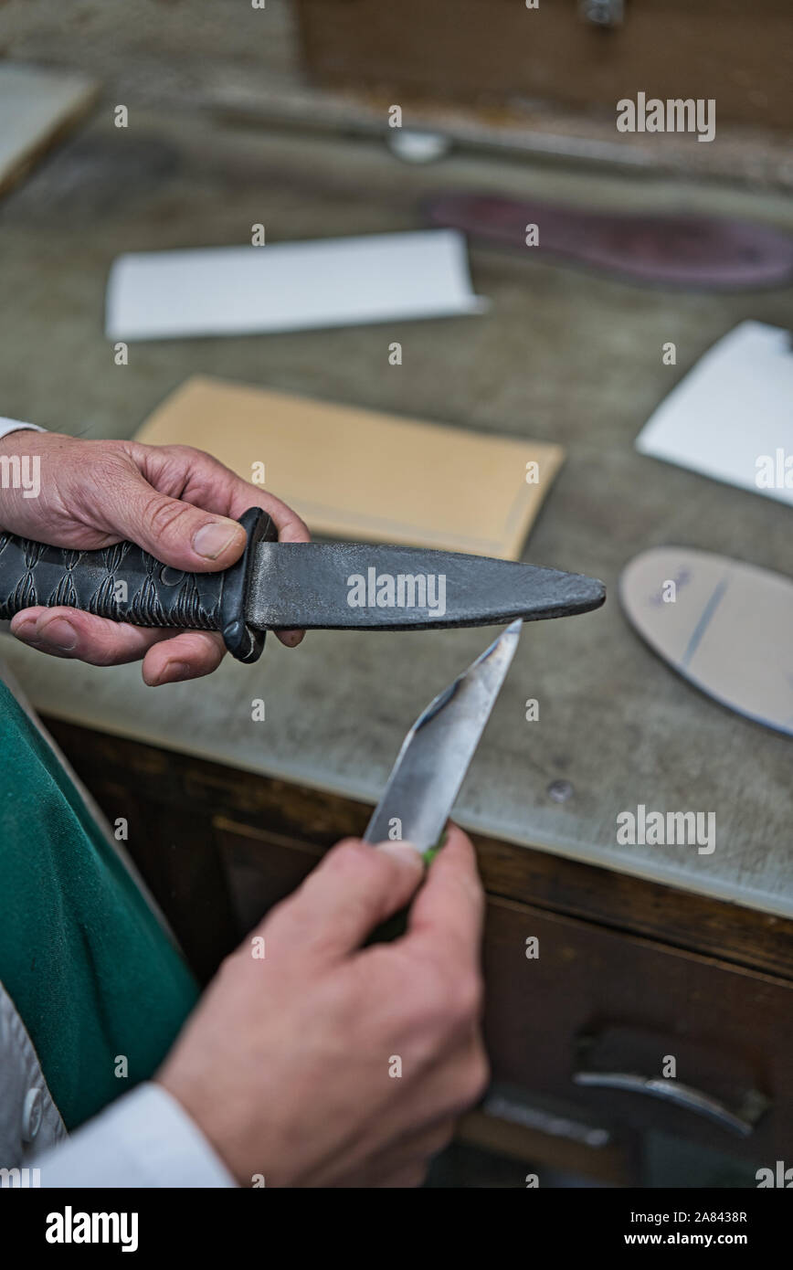 Craftsman's hands sharpening the edge of the cutter with a knife ...