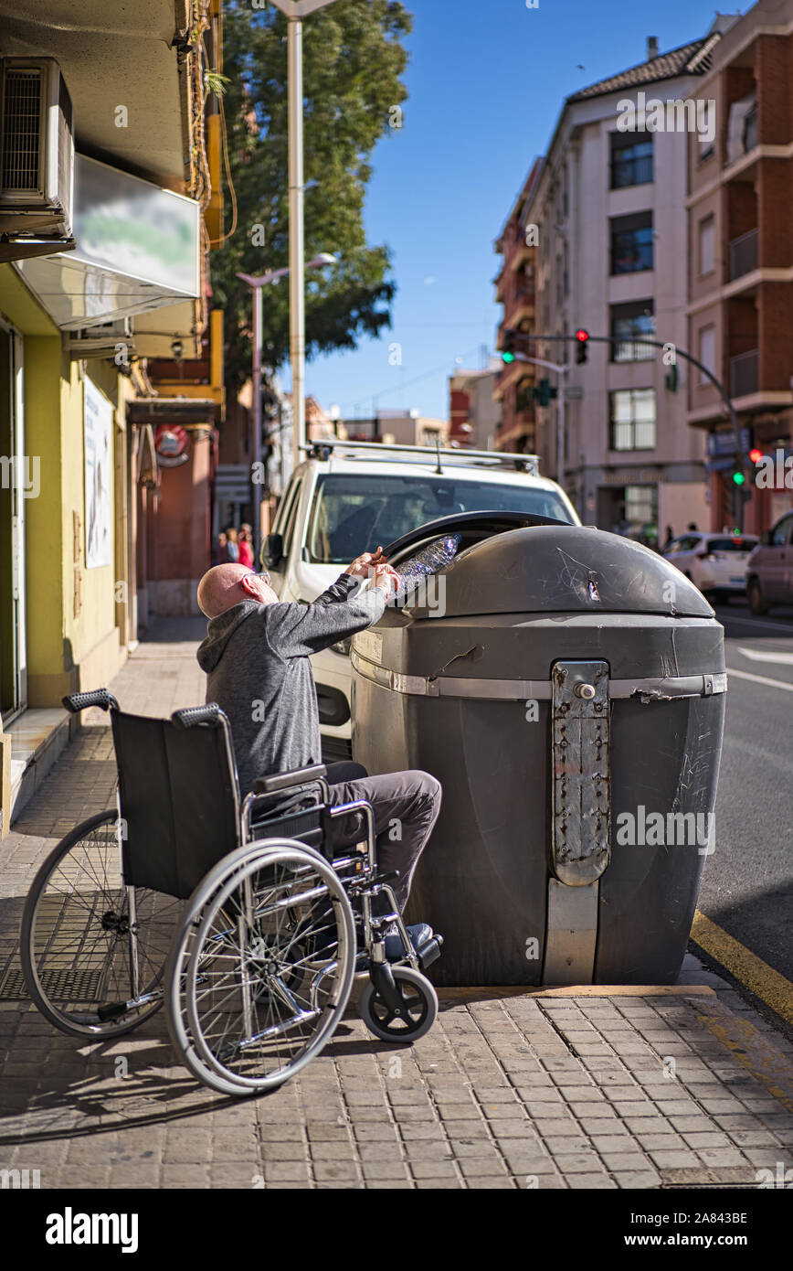 Wheelchair disabled person picking up a transparent plastic bottle ...
