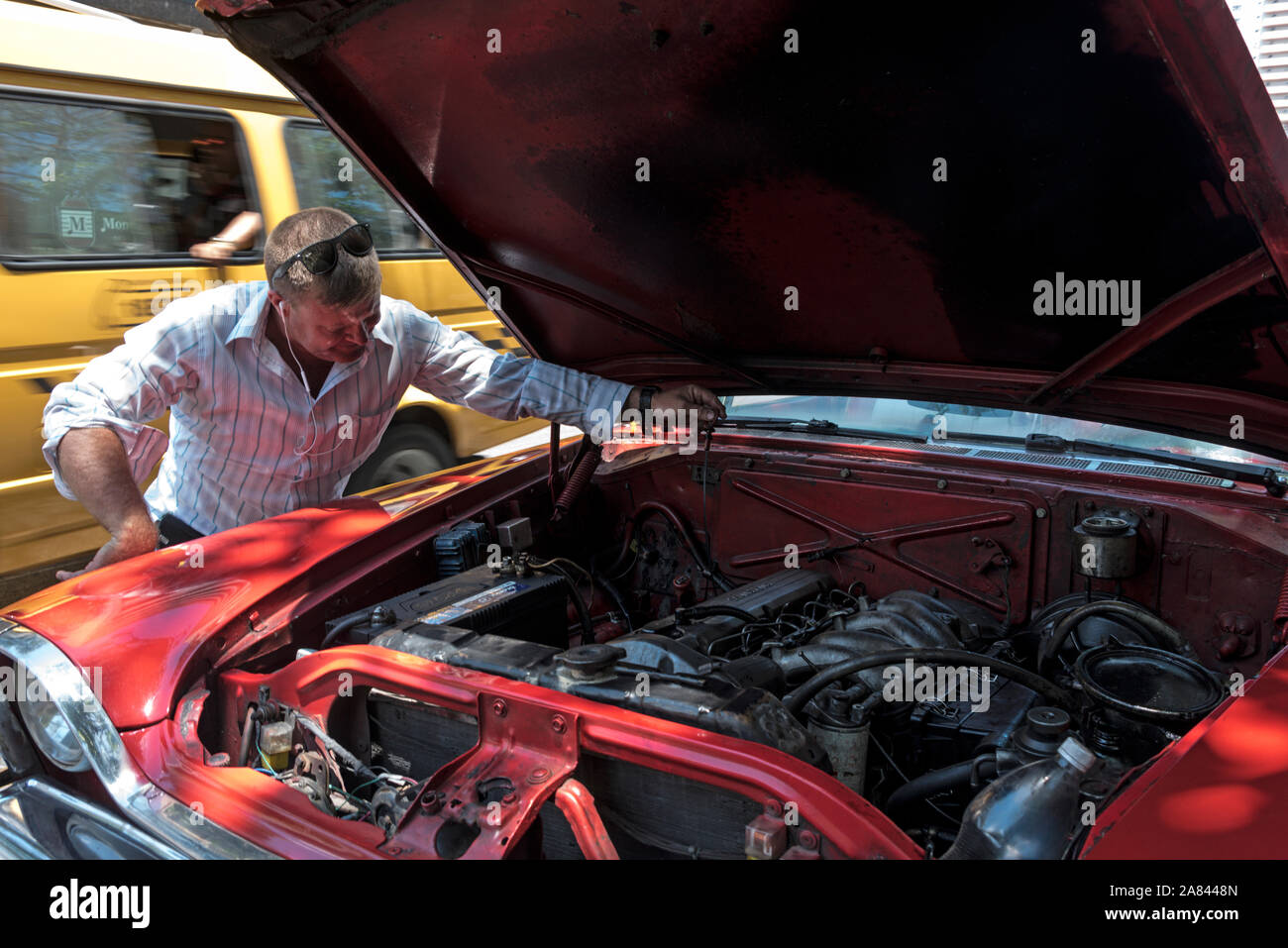 An American classic car taxi driver, checking his engine oil with a ...