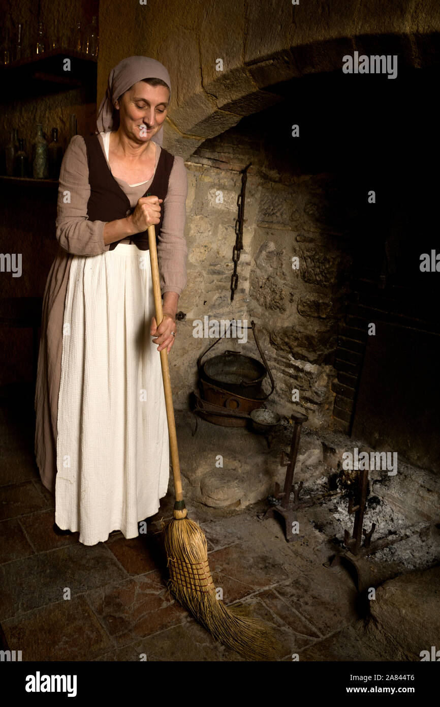 Woman dressed in renaissance maid costume using her broom to clean the ...