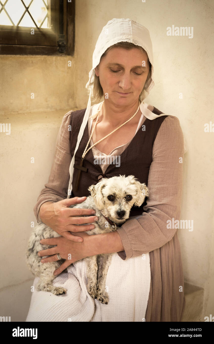 Woman in authentic medieval peasant outfit sitting with her dog in a ...