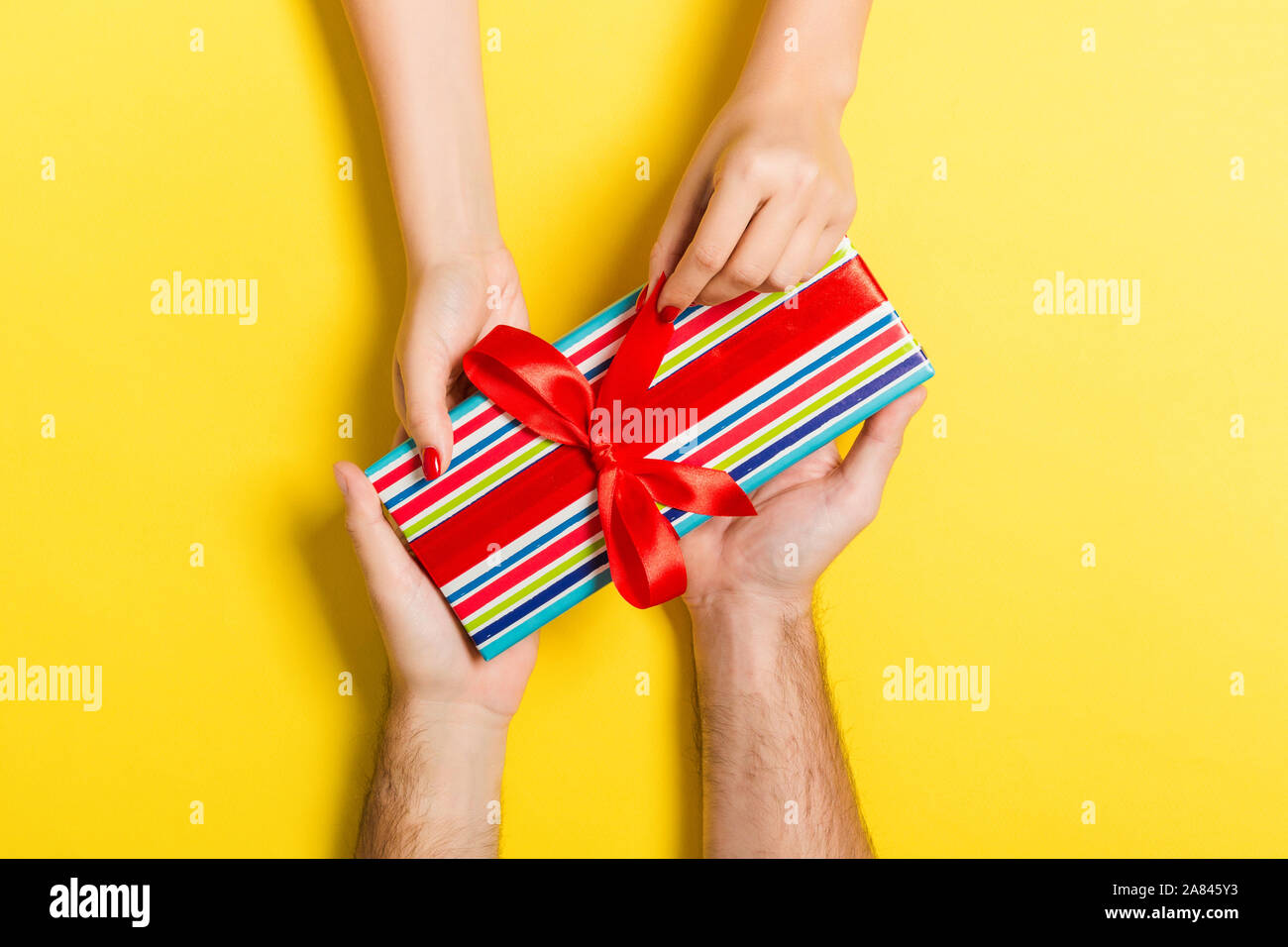 Top view of giving and receiving a gift on colorful background. Present ...