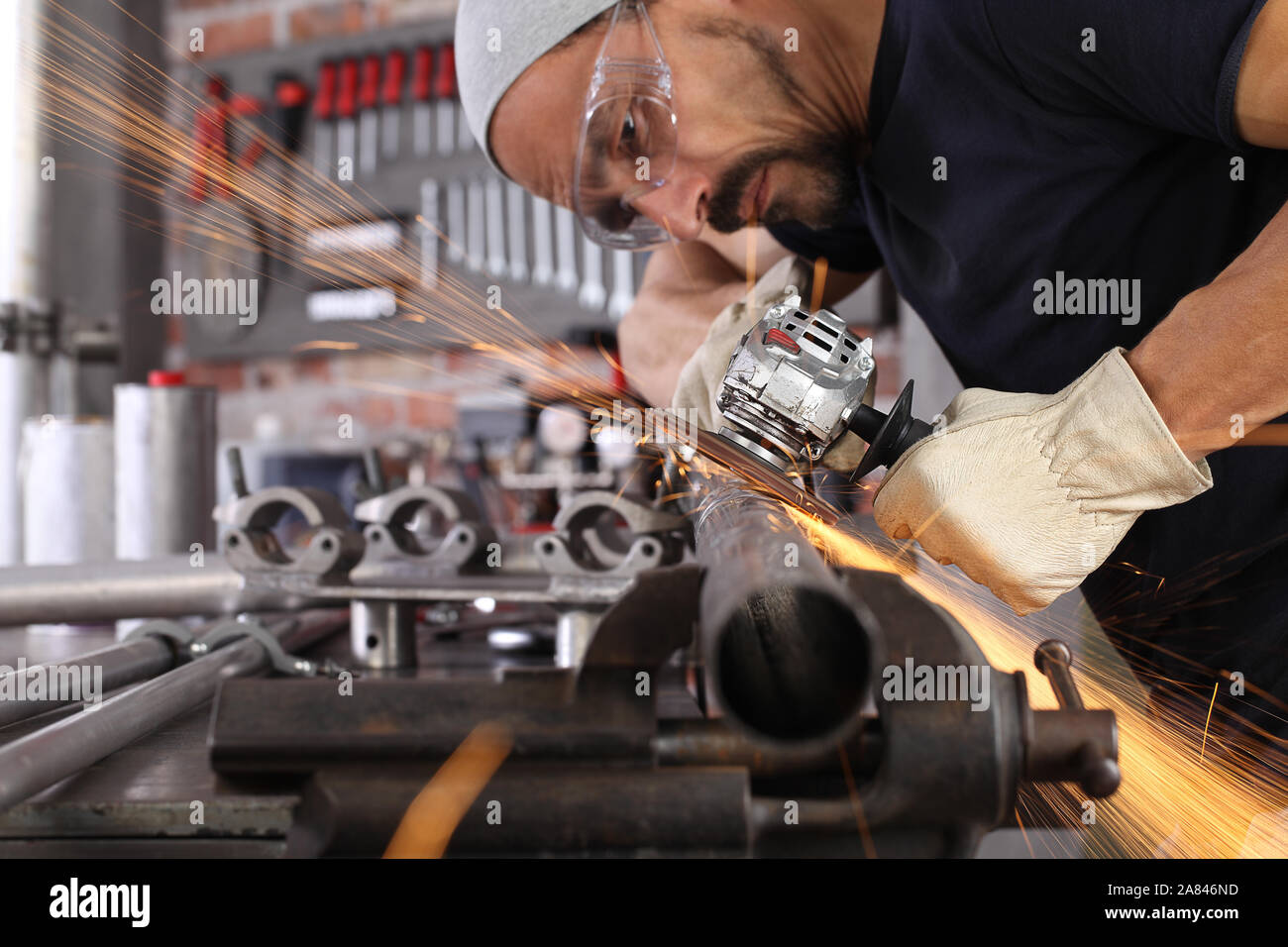 man work in home workshop garage with angle grinder, goggles and ...