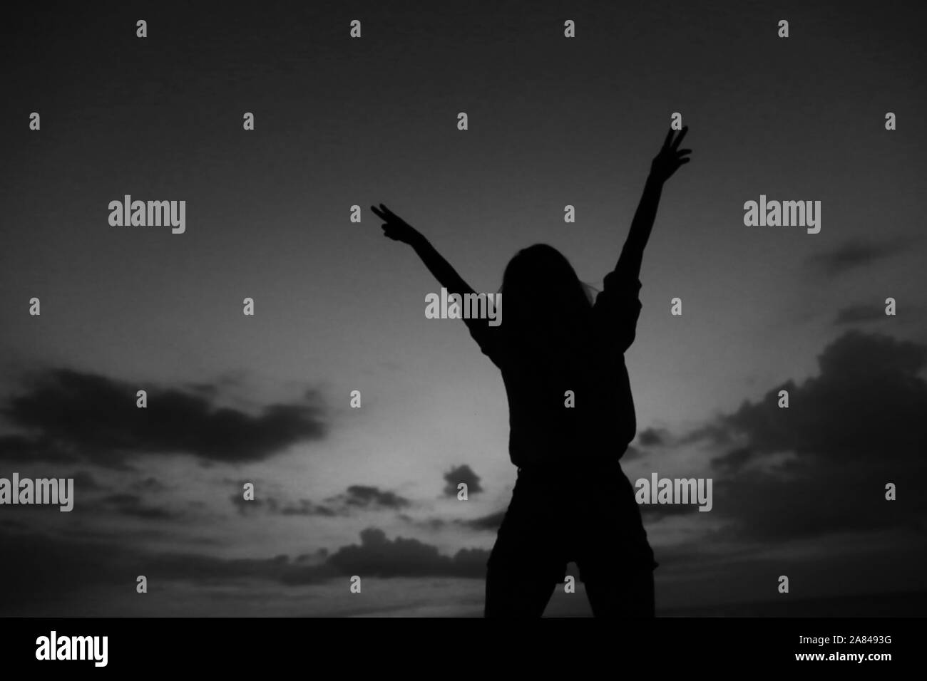 Black female silhouette with raised hands on grey sunset sky in Los ...