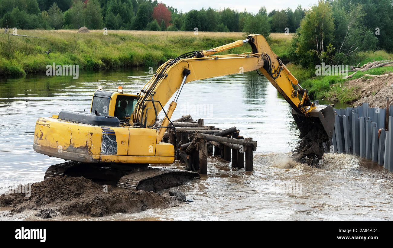Excavator working in the small forest river, excavator bucket ...