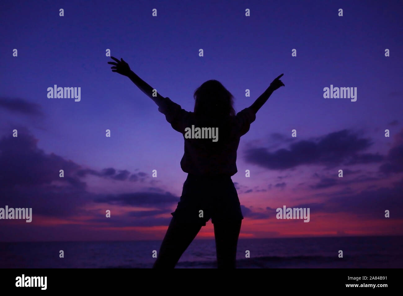 Black female silhouette on violet sunset sky with clouds in backround ...