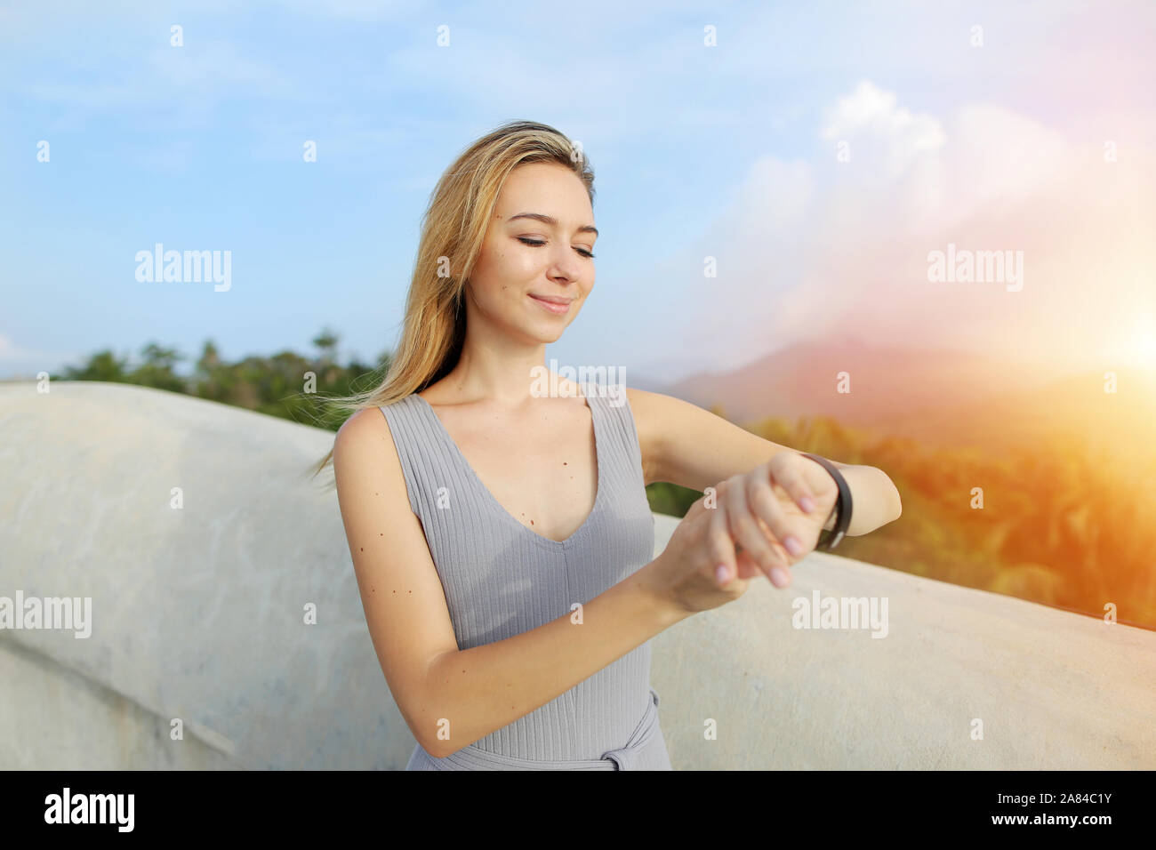 Sunshine portrait of young caucasian girl using smartwatch, mountains ...