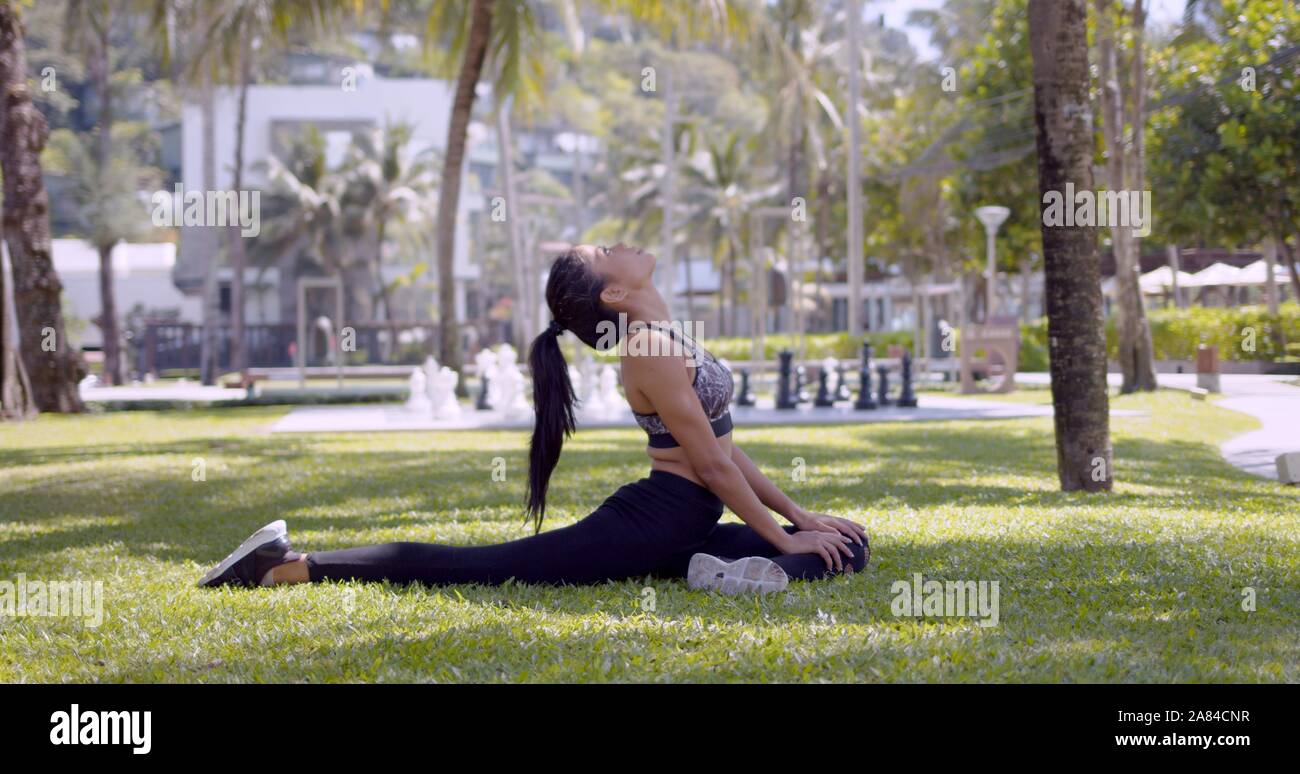 Asian slim woman stretching neck and legs sitting in park Stock Photo ...