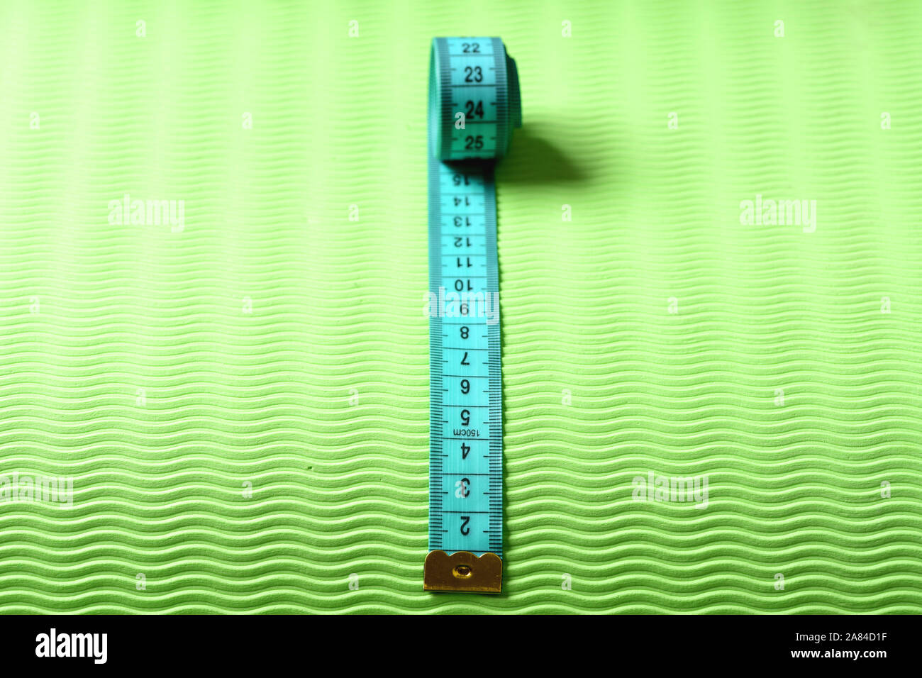 Measuring tape roll in cyan color on green texture background. Sports ...