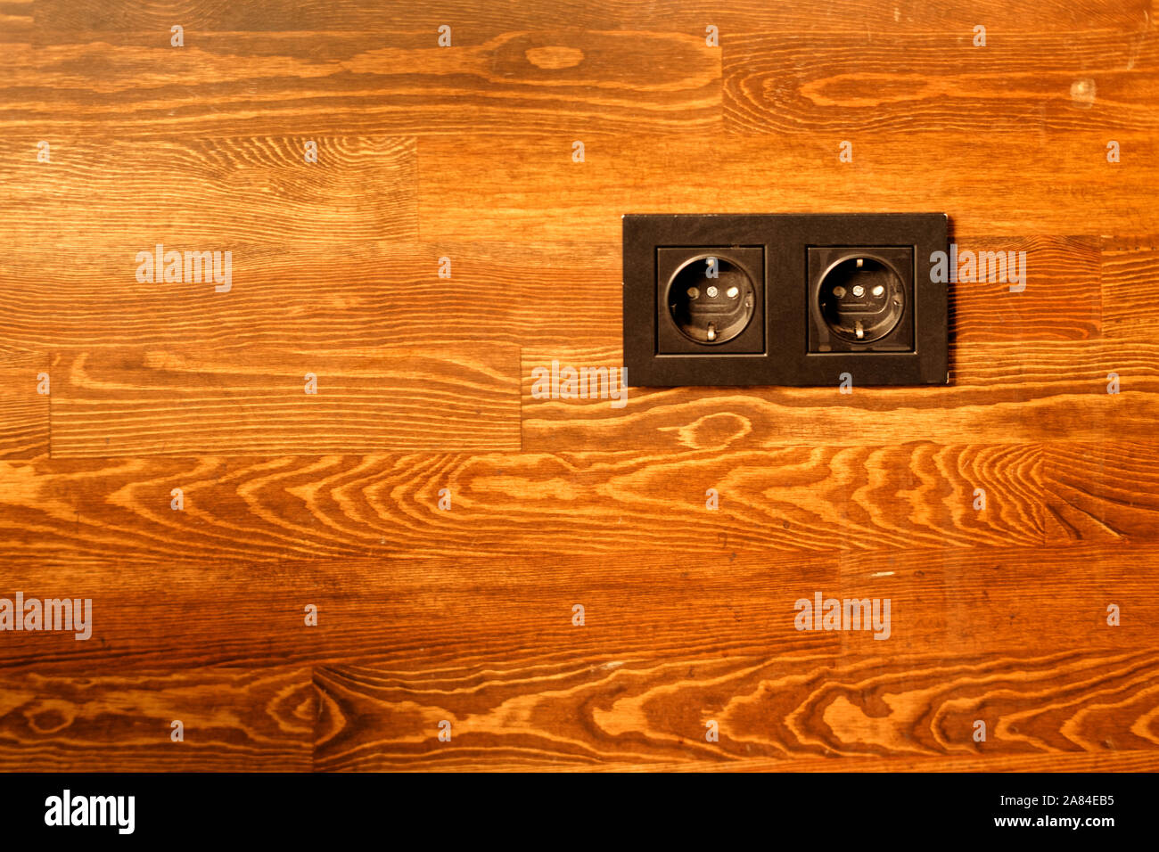 Black power outlet on brown varnished wood wall Stock Photo - Alamy