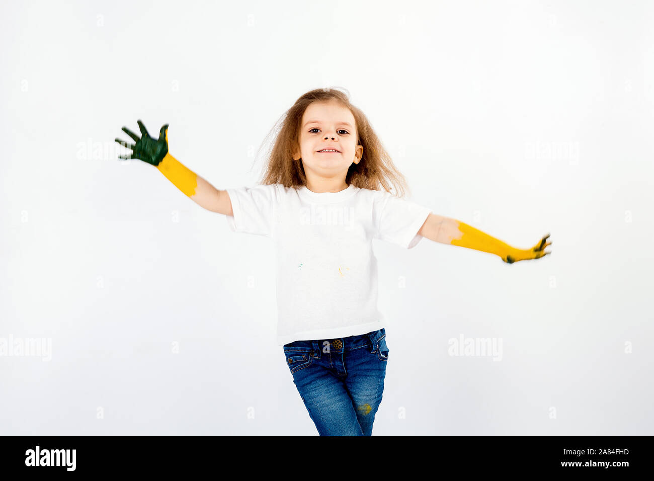 Adorable little girl, modern hair style, white shirt, blue jeans poses ...