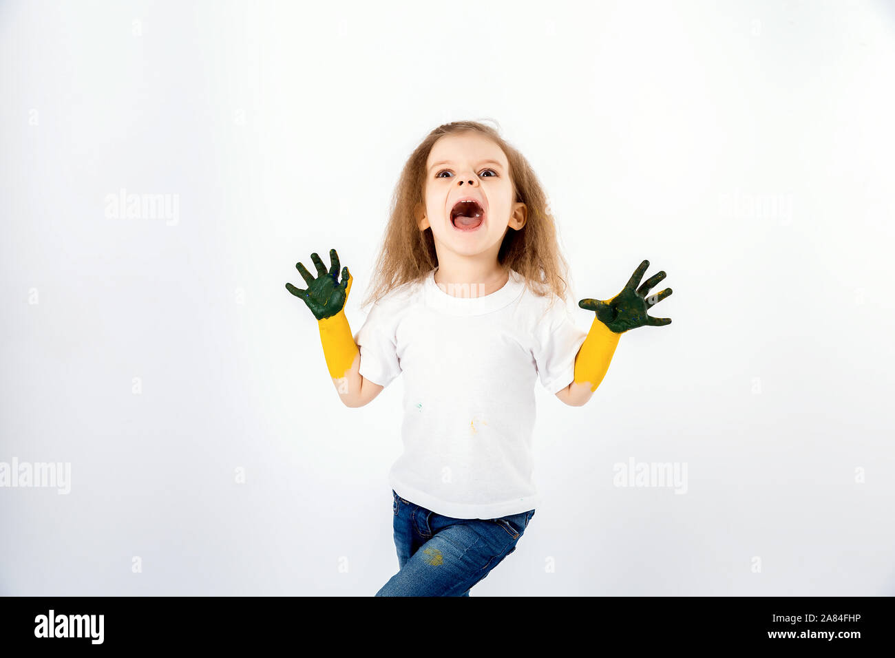 Adorable little girl, modern hair style, white shirt, blue jeans poses ...