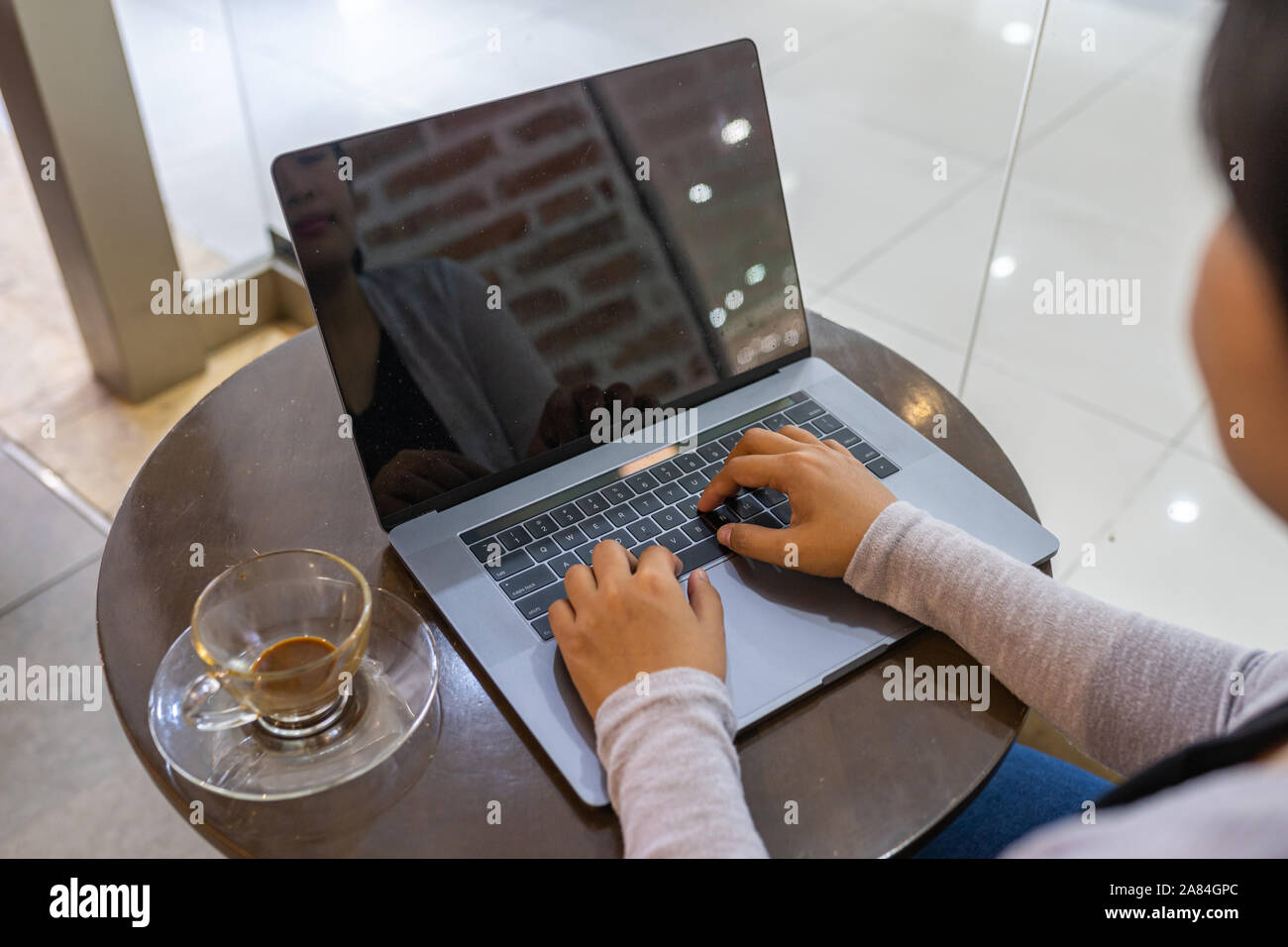 Woman hand typing laptop keyboard at round coffee table Stock Photo - Alamy
