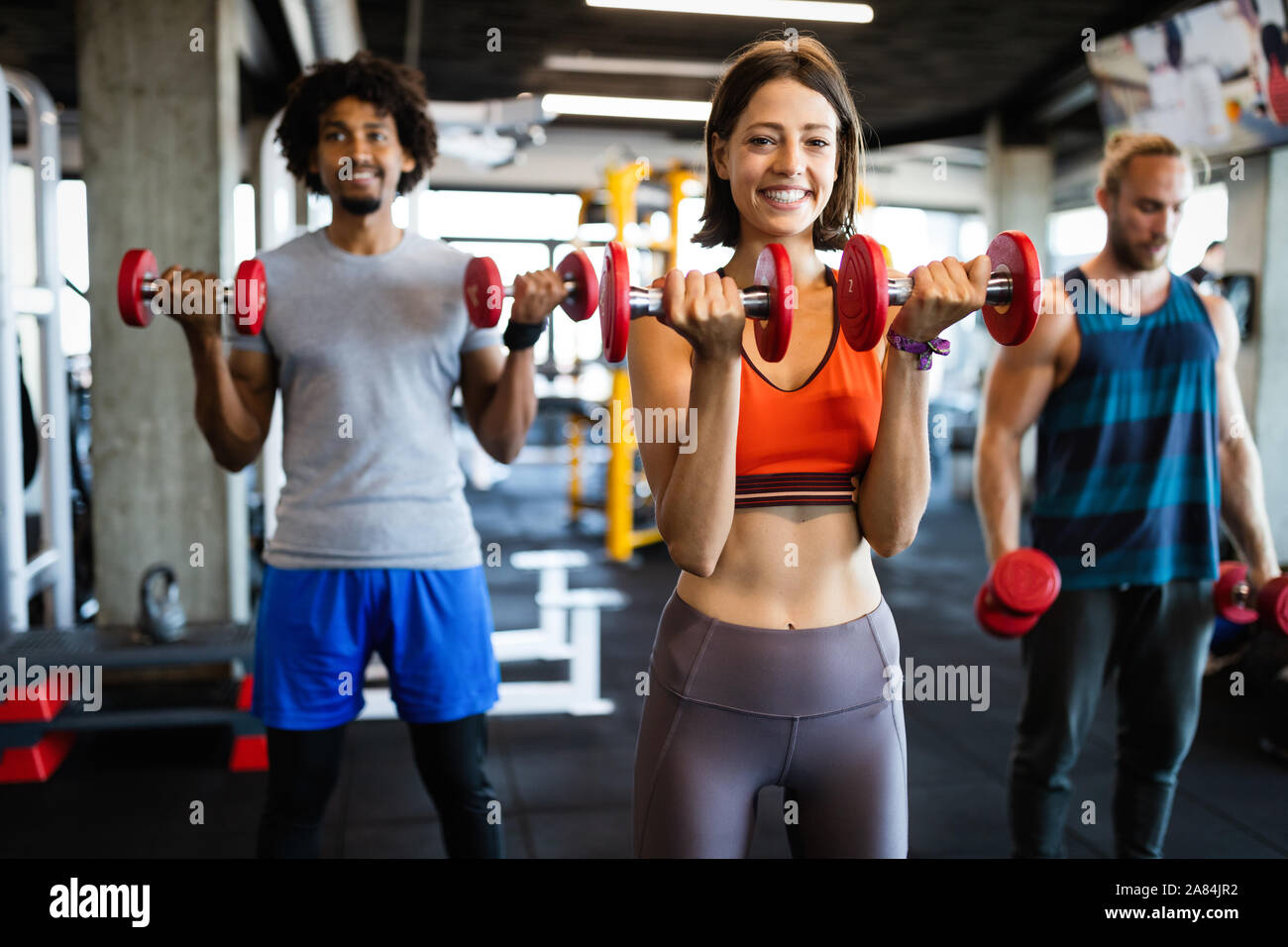 Healthy young people doing exercises at fitness studio Stock Photo - Alamy