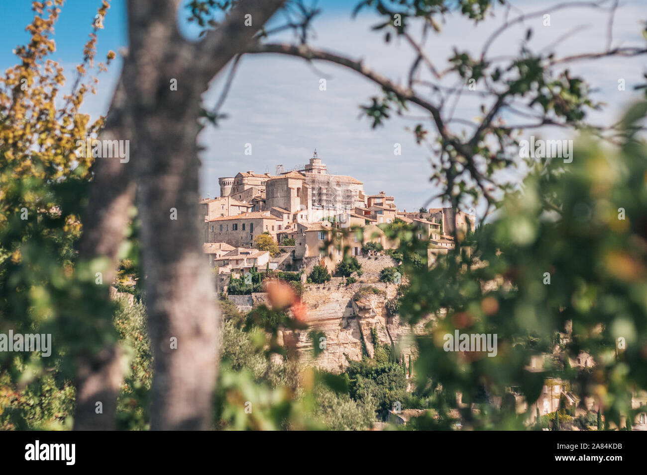 Beautiful view of the city of Gordes through the branches of a tree ...
