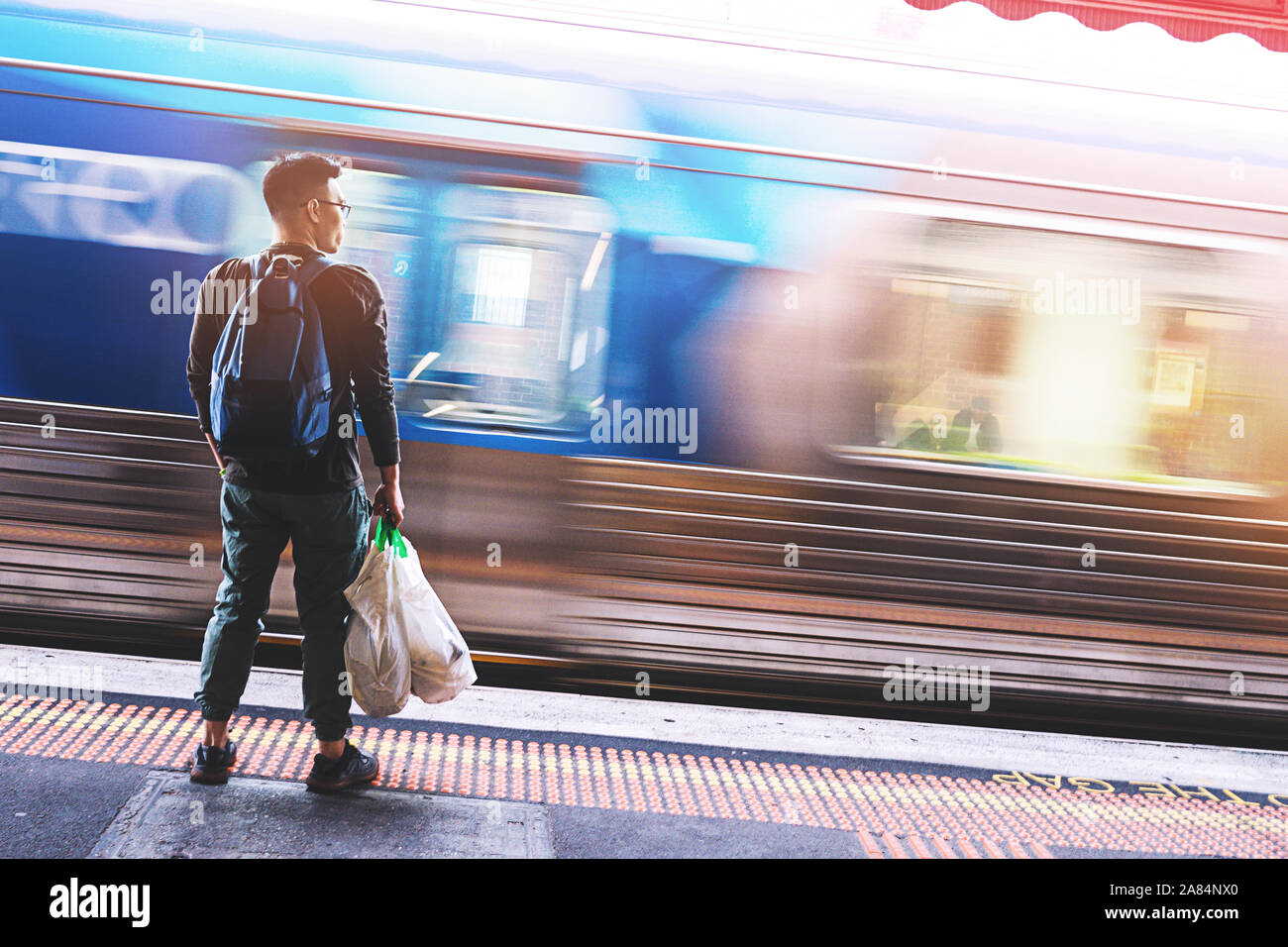 Back of a man waiting for the train under the sunlight at station in ...