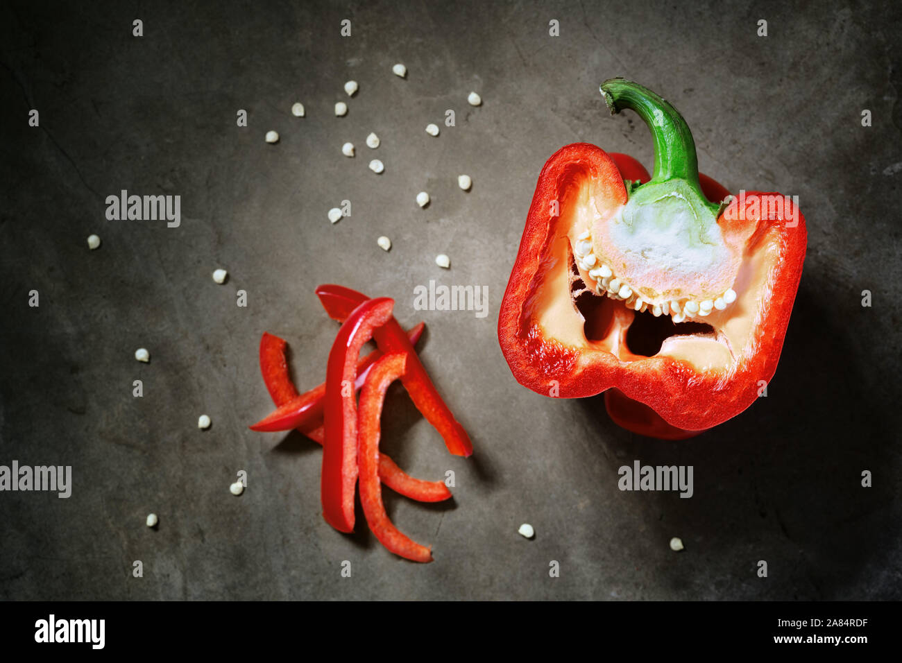 One Red pepper on dark moody background sliced in half with a top view ...