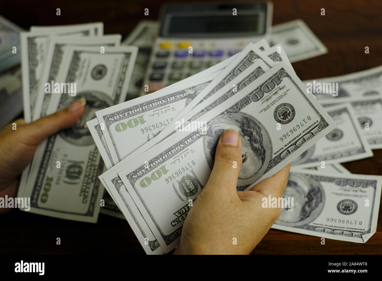 Businessmen women counting money on a stack of 100 US dollars banknotes ...