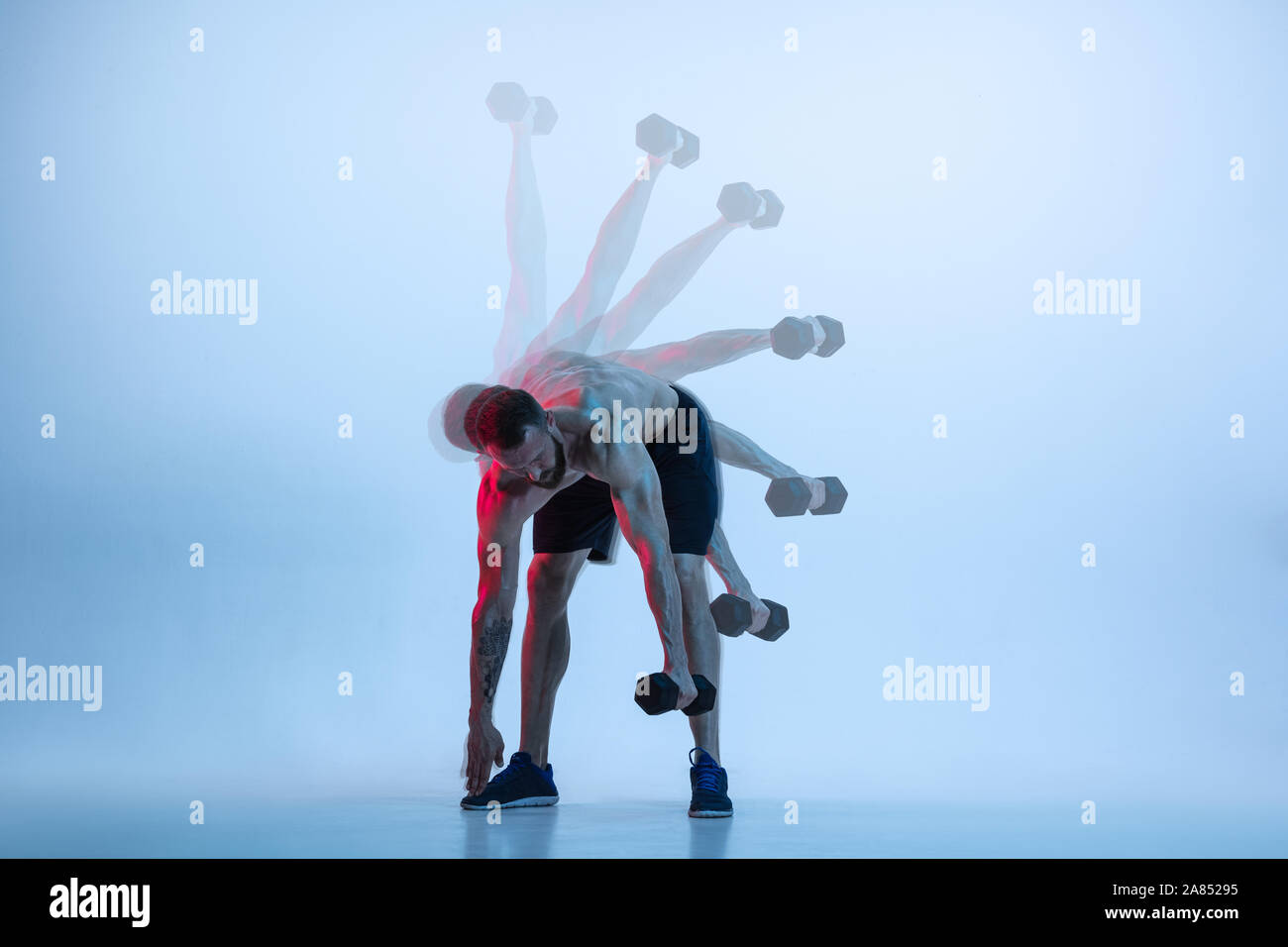 Flying. Young caucasian bodybuilder training over studio background in ...