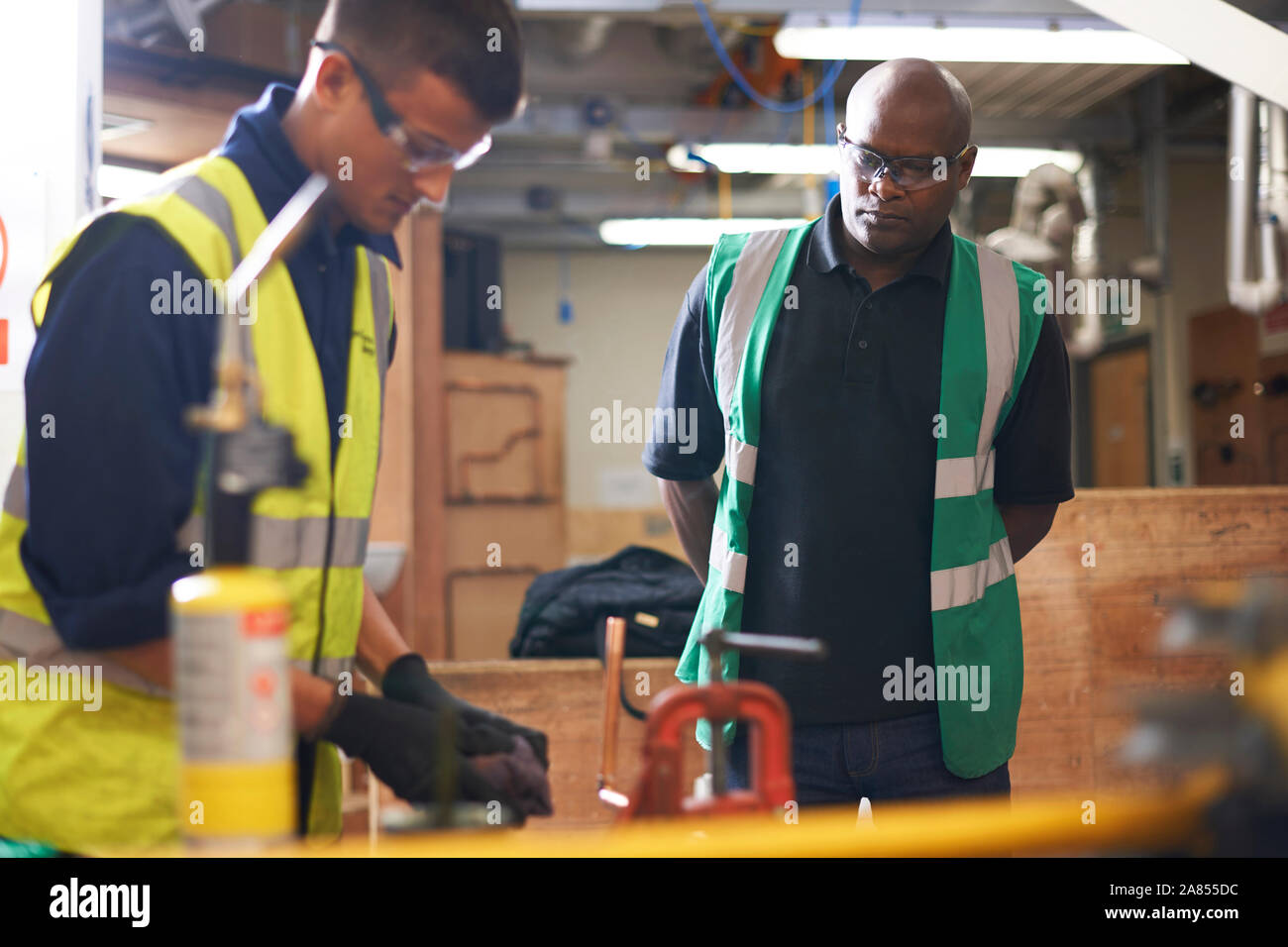Shop class teacher watching student in workshop Stock Photo - Alamy