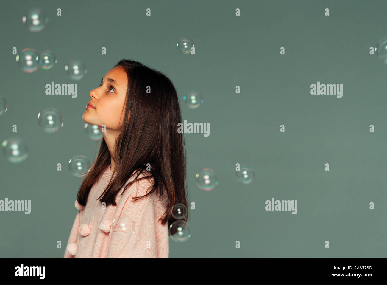 Serene, curious girl watching falling bubbles Stock Photo - Alamy