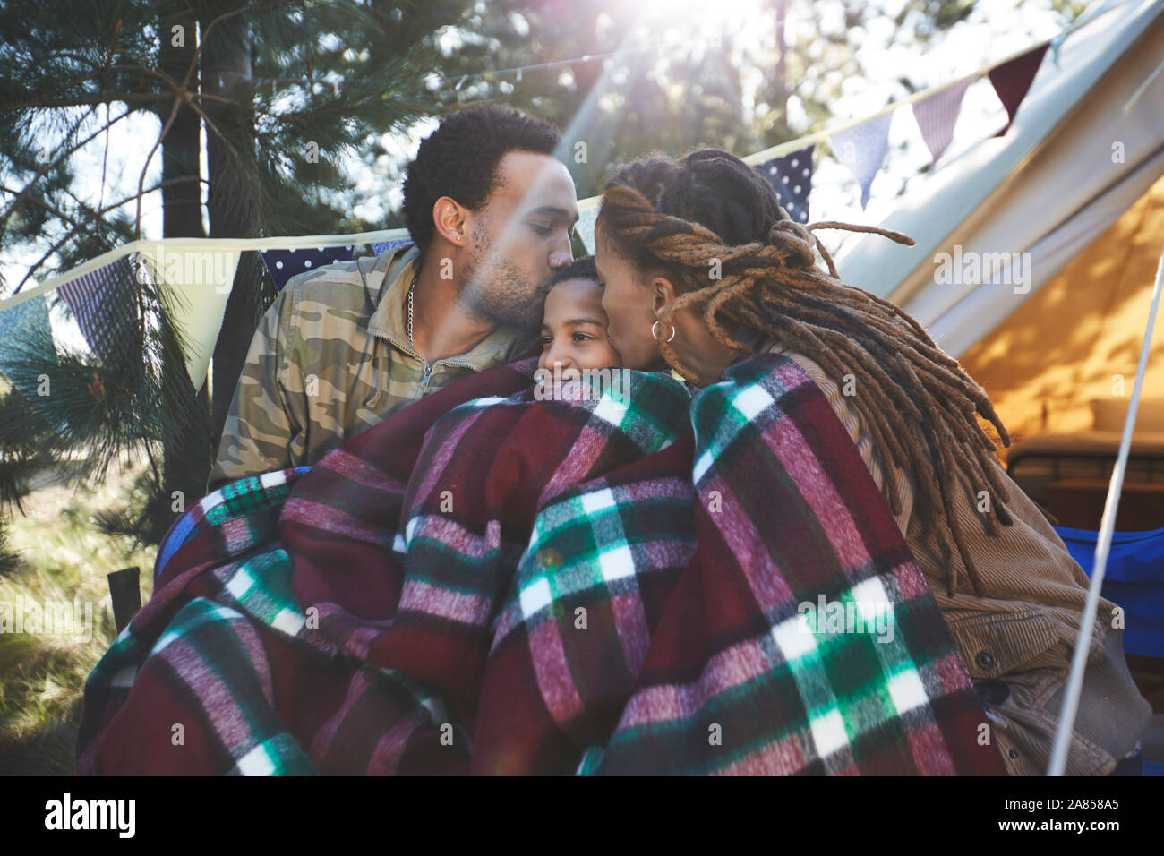 Happy, affectionate parents kissing son, relaxing at campsite Stock ...
