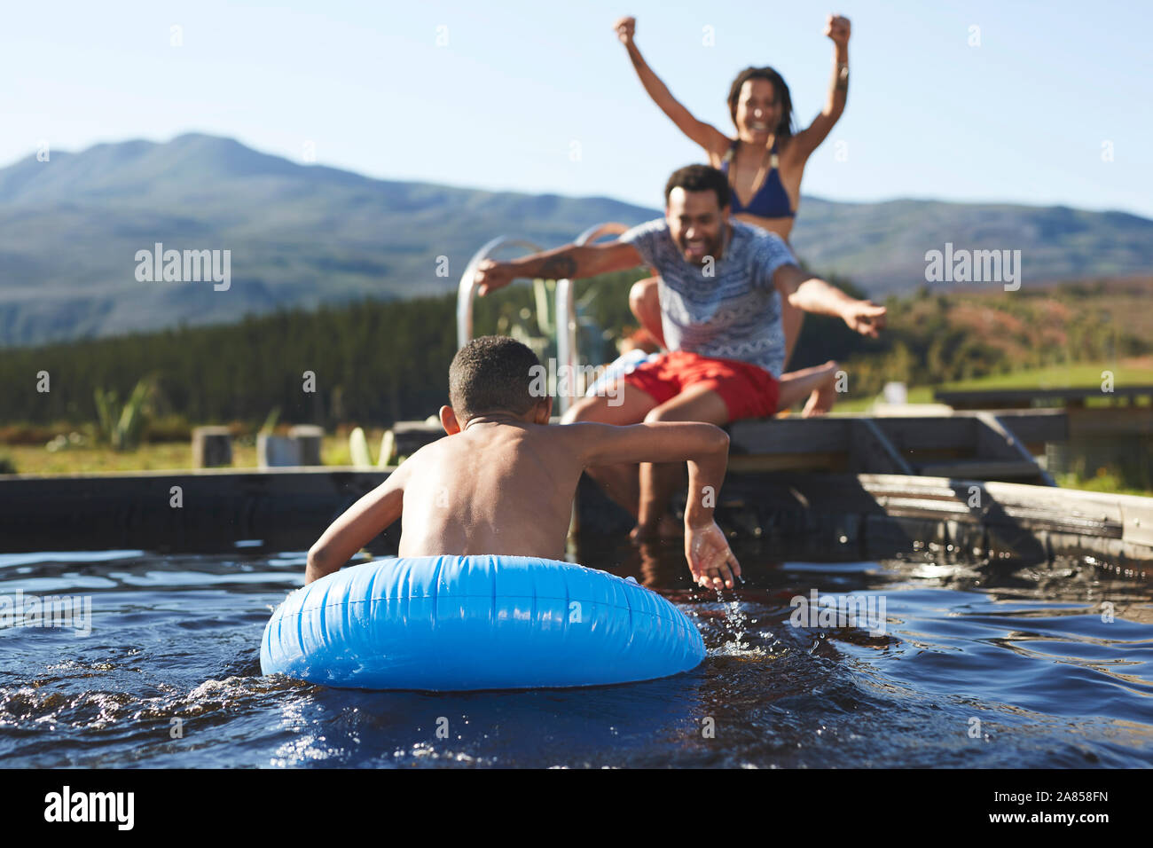Playful family swimming in sunny, summer swimming pool Stock Photo - Alamy
