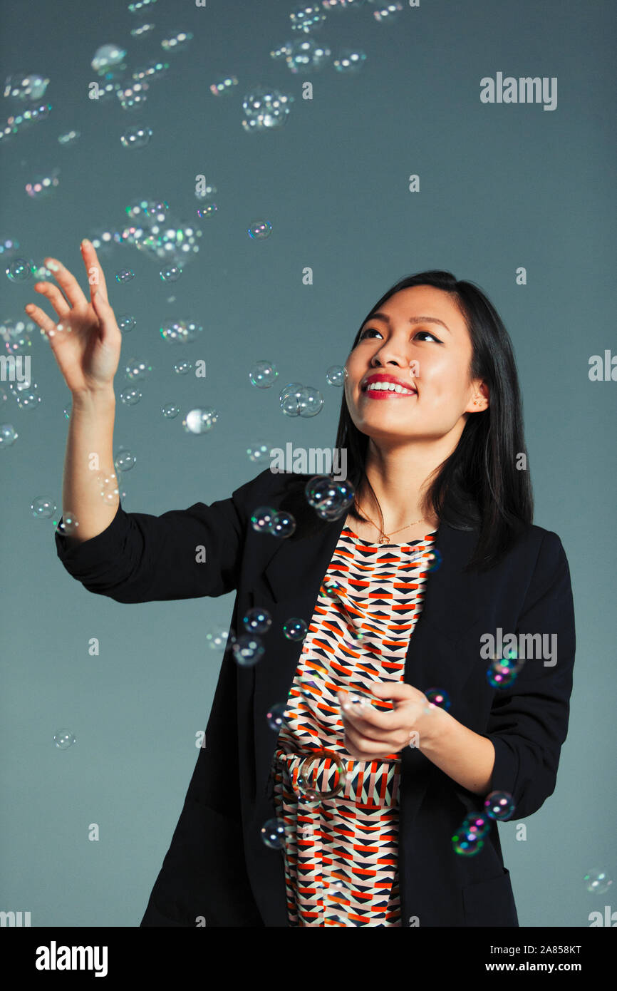 Portrait happy, playful businesswoman watching falling bubbles Stock ...