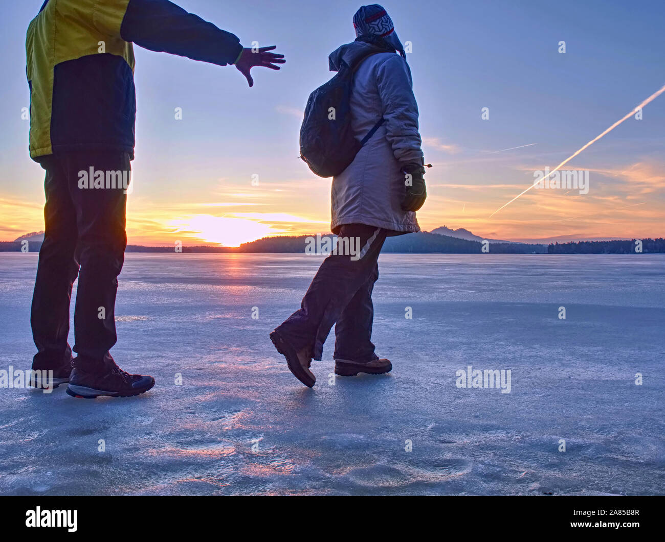 Tourist couple is spending time outdoors on a frozen lake, watching ...