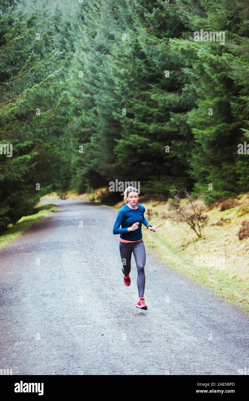 Woman running on trail in remote woods Stock Photo - Alamy