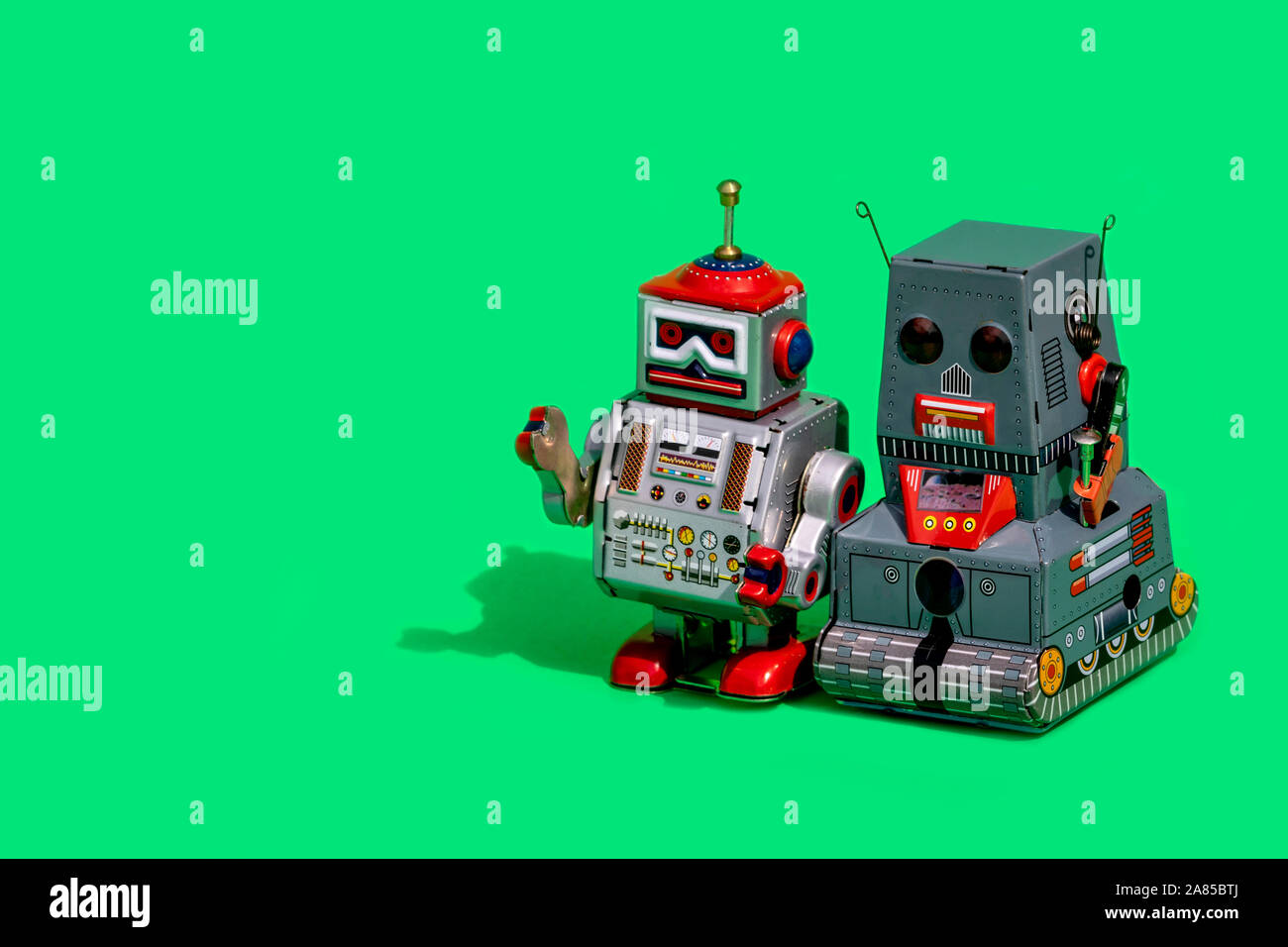 Two antique tin toy robot on green background. Vintage and classic ...