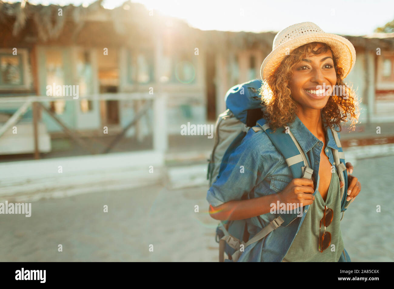 Portrait happy young female backpacker outside sunny beach hut Stock ...