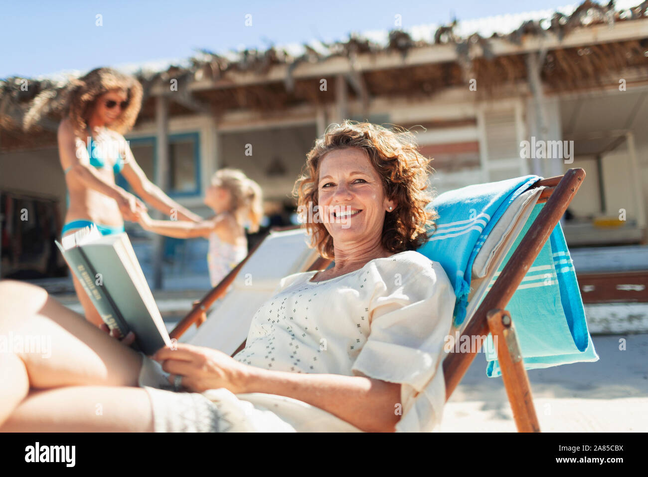 Portrait happy woman reading book, relaxing on sunny beach Stock Photo ...
