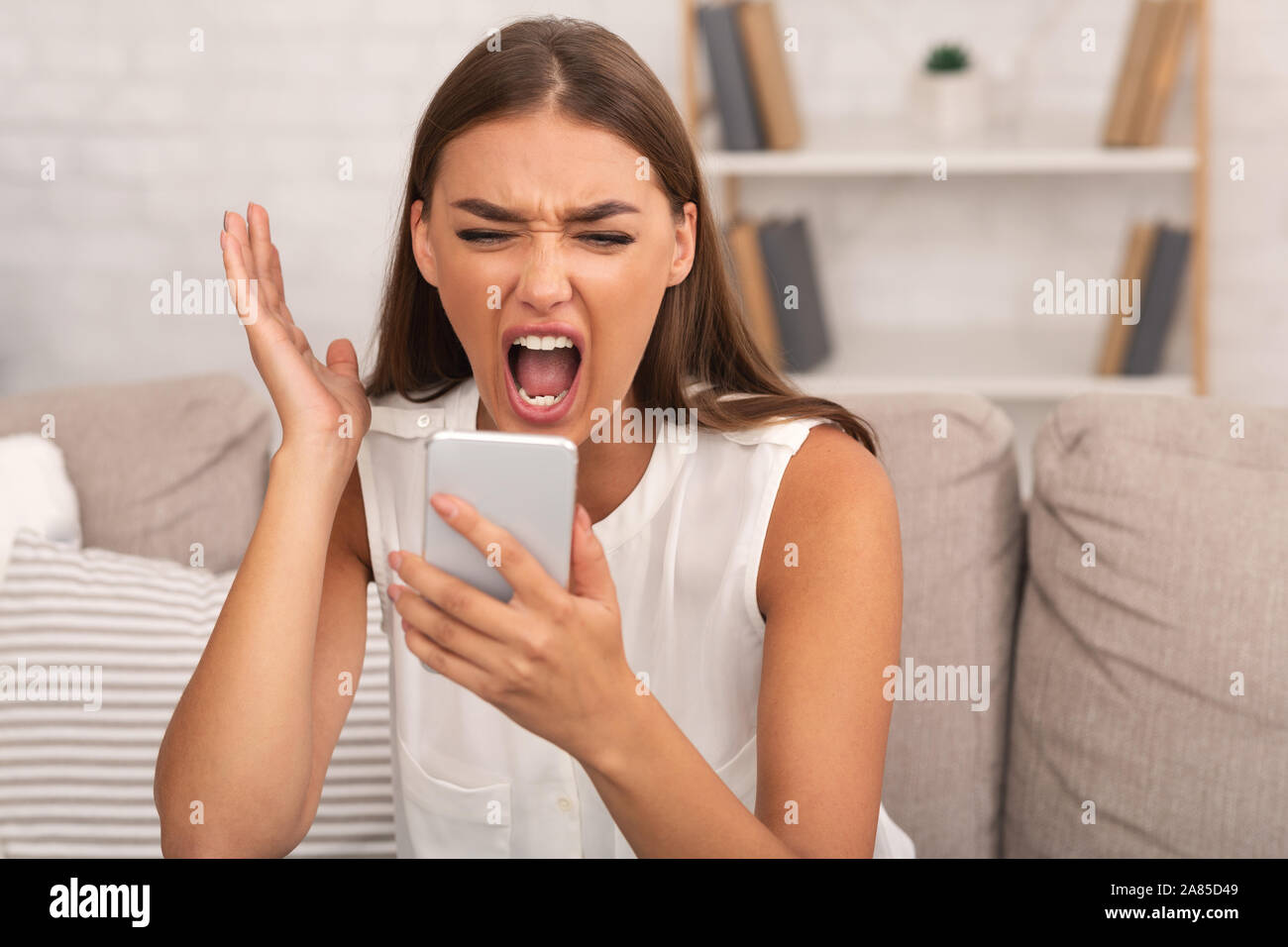 Furious Lady Shouting On Smartphone Sitting On Couch At Home Stock ...