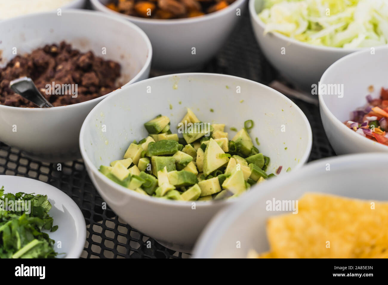 Tortilla dipping into smashed avocado, green guacamole dip Stock Photo ...