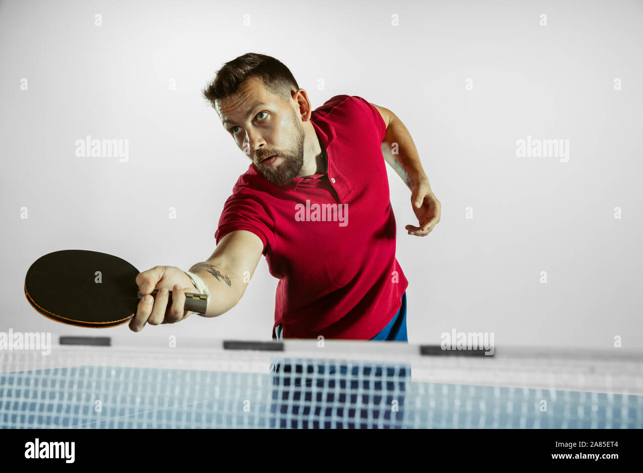 Strong. Young man plays table tennis on white studio background. Model ...