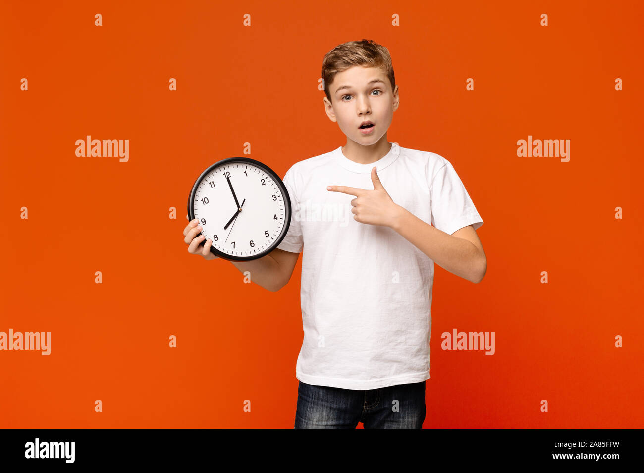 Anxious teenage boy pointing at alarm clock Stock Photo - Alamy