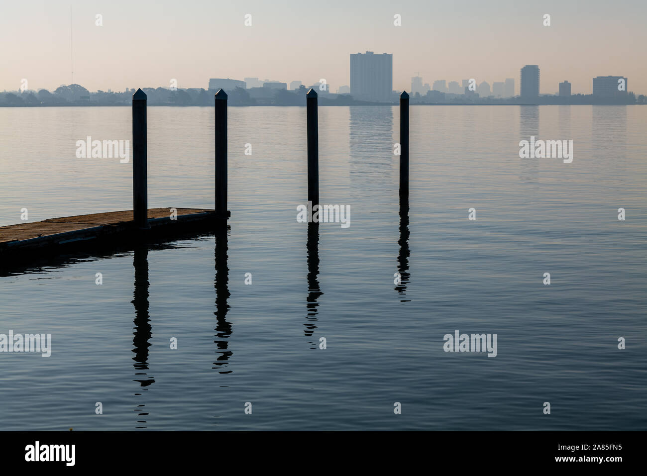 Boat Dock extending out into water with hazy city scape behind Stock ...