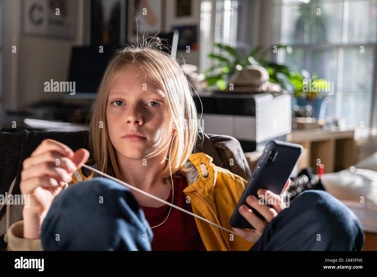 Tween boy sitting looking at camera holding phone Stock Photo - Alamy