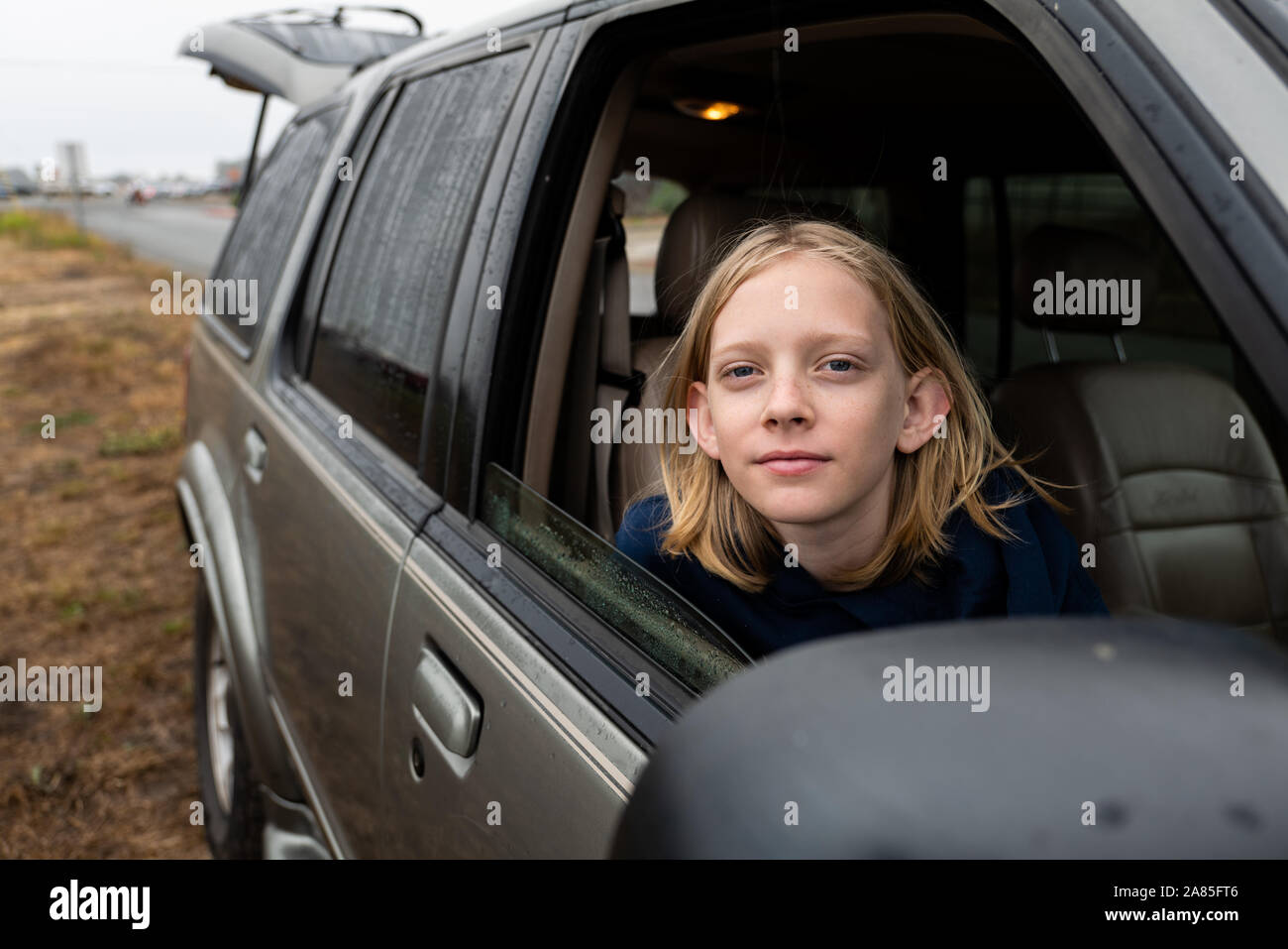 Tween looking at camera from passenger seat of SUV Stock Photo - Alamy