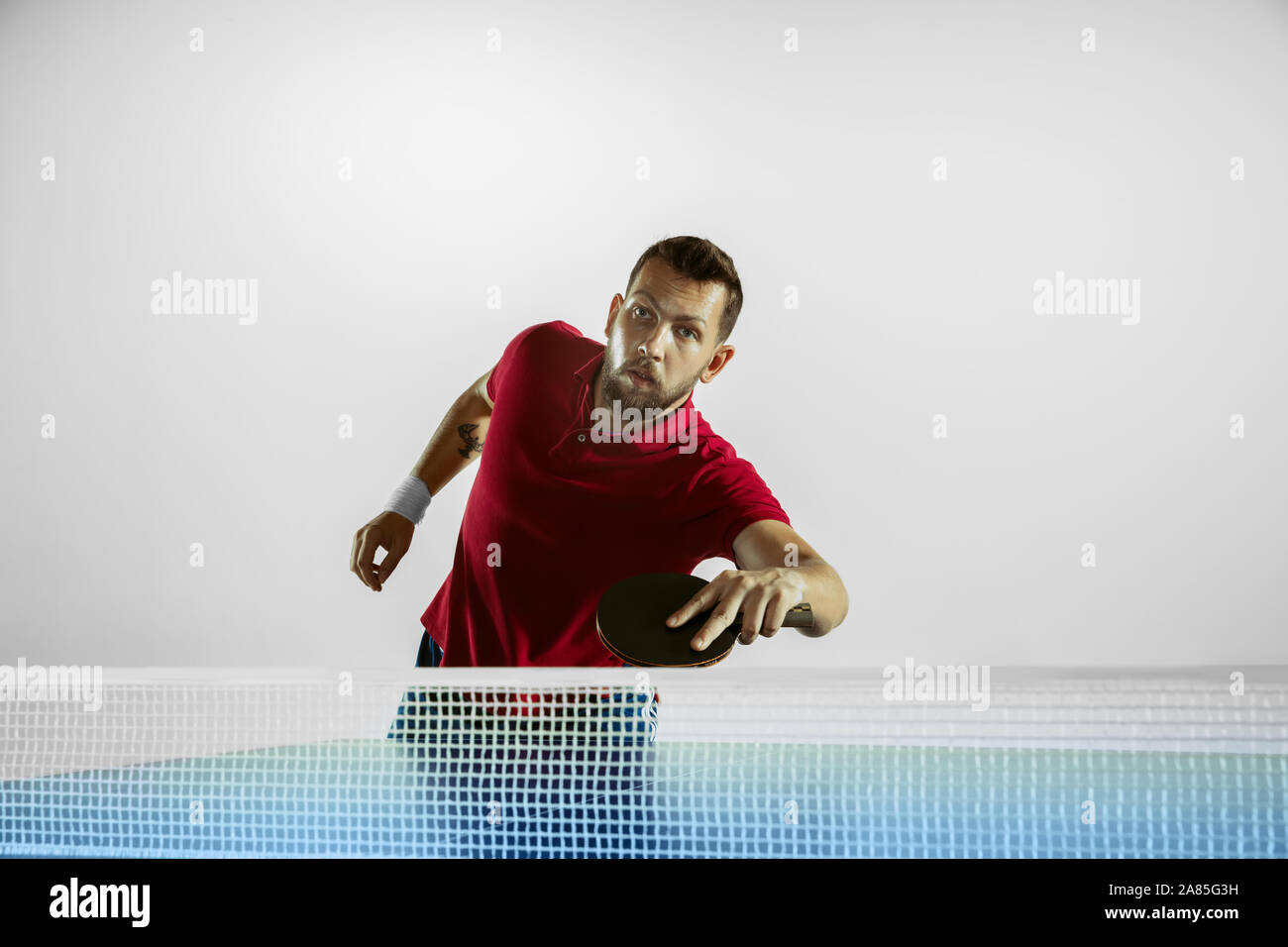 Aspiring. Young man plays table tennis on white studio background ...