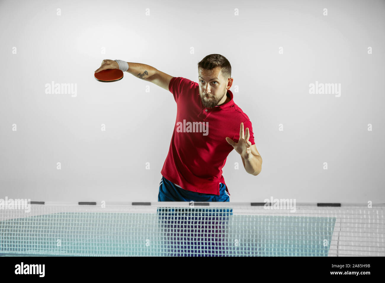 Thirst. Young man plays table tennis on white studio background. Model ...