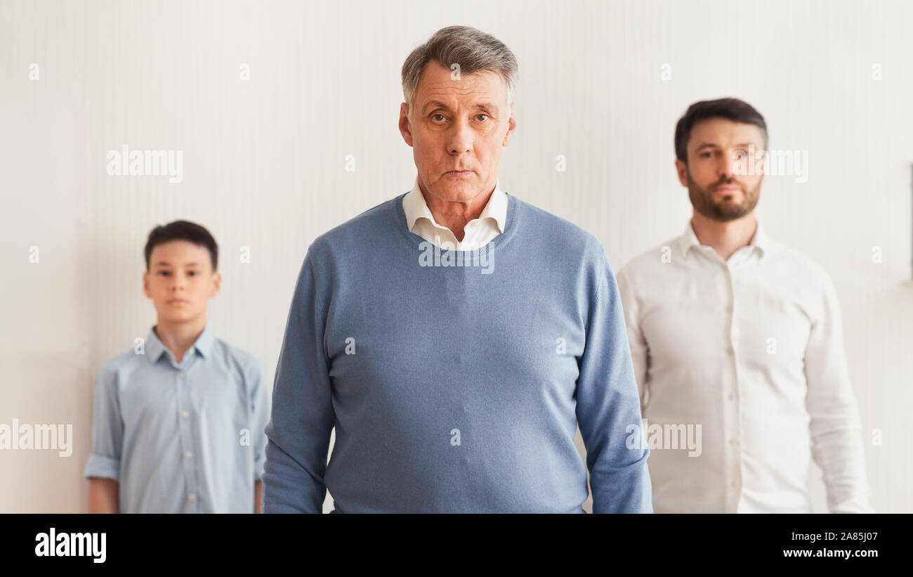 Grandfather Standing Between Son And Grandson Against White Wall ...