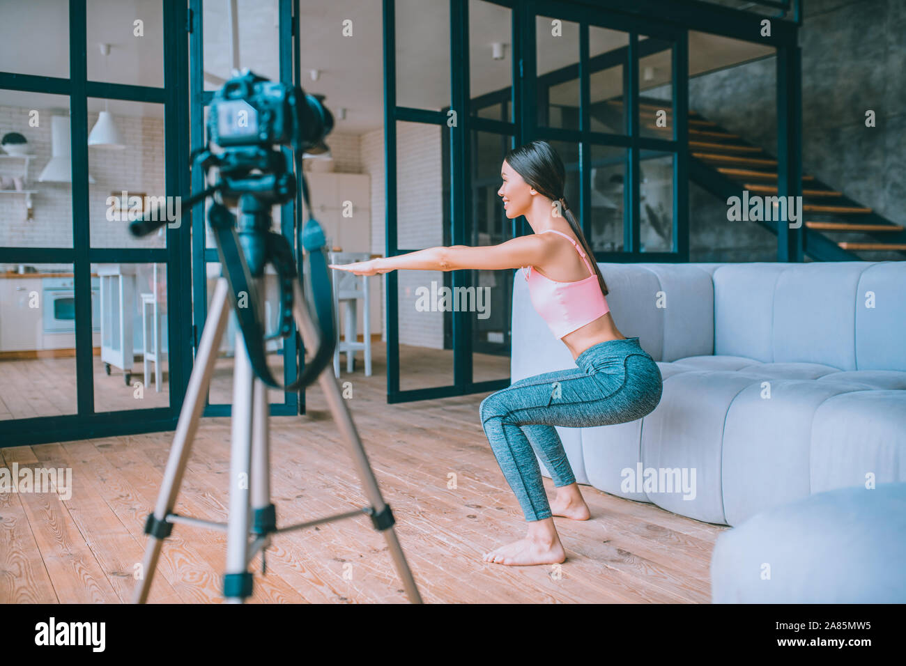 Slim fitness blogger doing sit ups while filming morning tutorial Stock ...