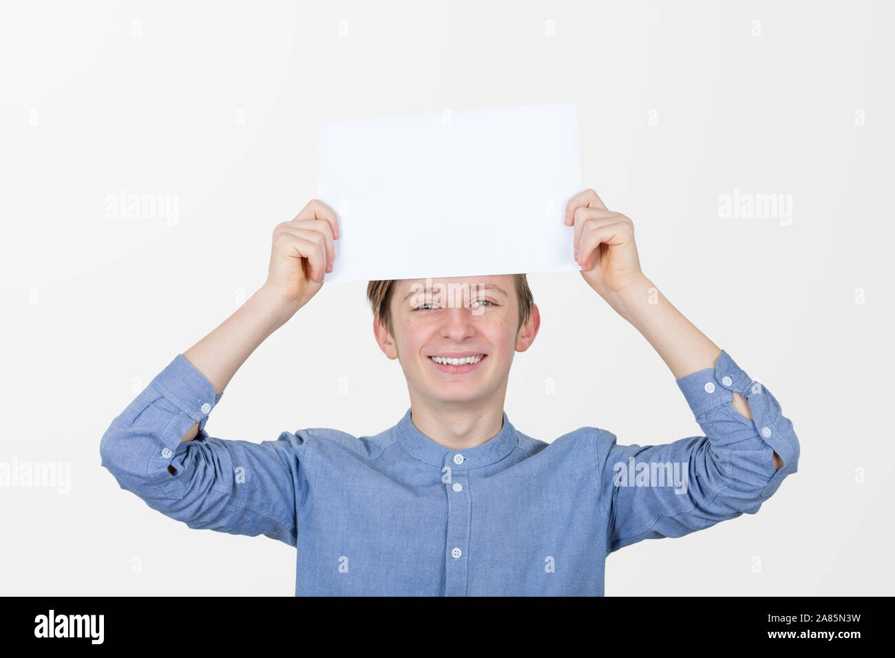 Smiling teenager boy holding a white paper above his head. Education ...